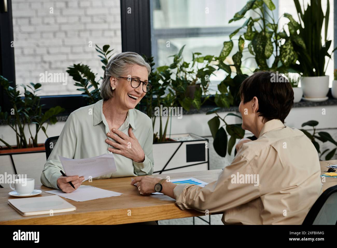 Two women engage in deep conversation at a table Stock Photo - Alamy