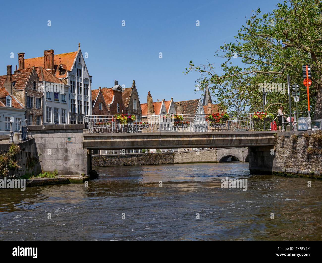 Stone bridge with flowers crossing a quiet canal, surrounded by ...