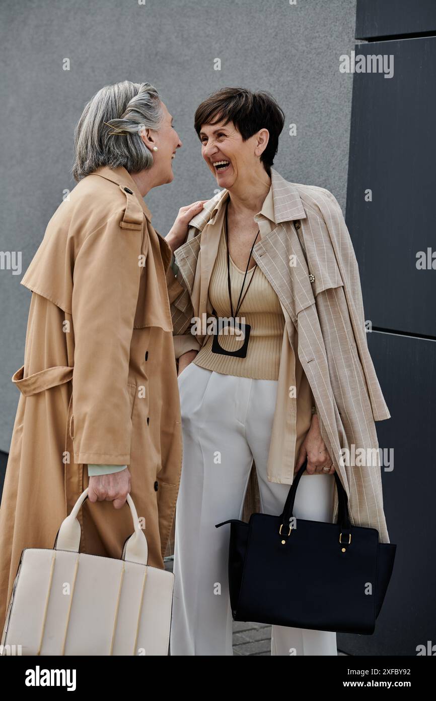 Two women standing together with bags Stock Photo - Alamy