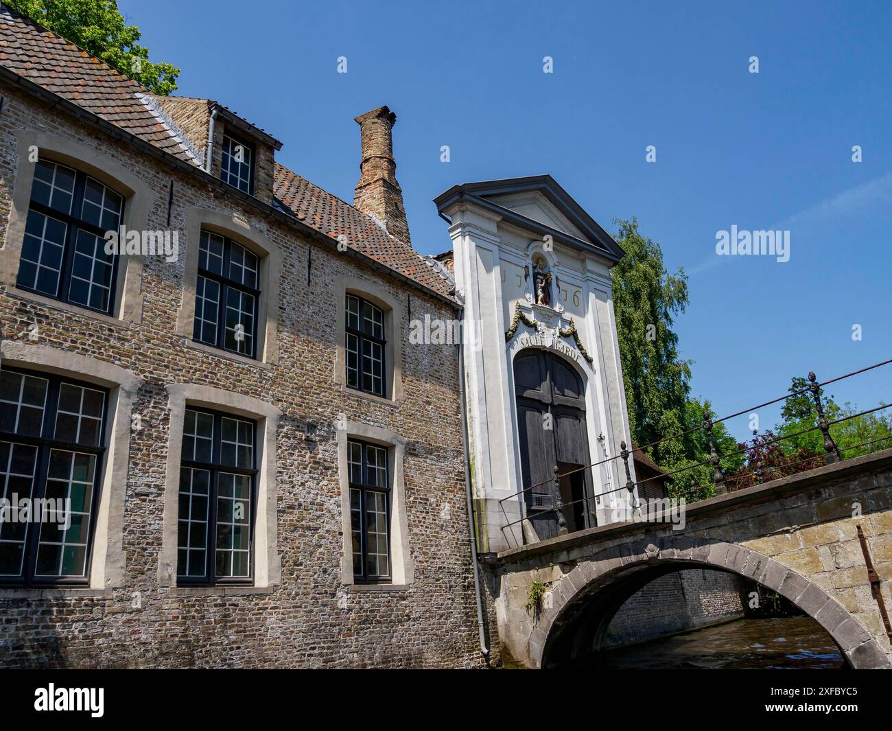 Stone bridge over a small river in front of historic buildings, Bruges ...