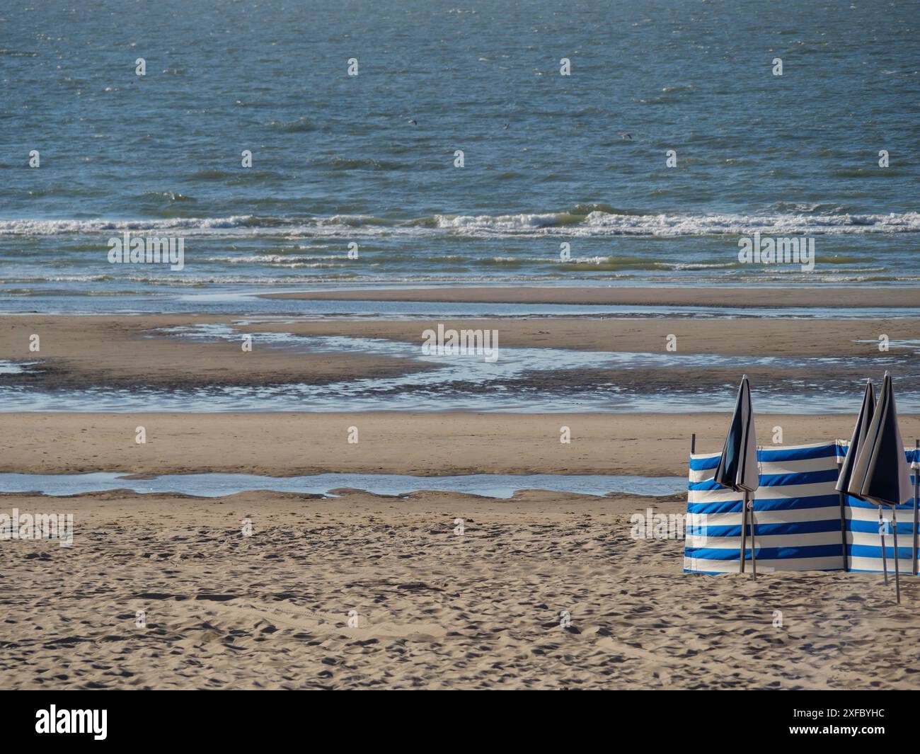 Beach with blue and white striped fence and view of the sea with waves ...
