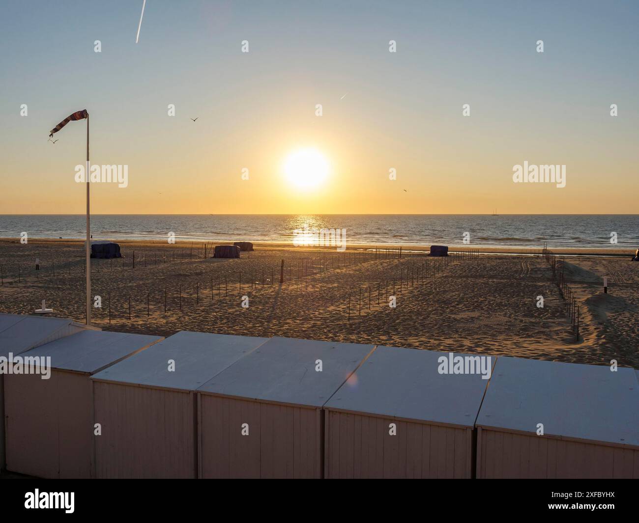 Sunset on the beach with scattered beach huts, De Haan, Flanders ...