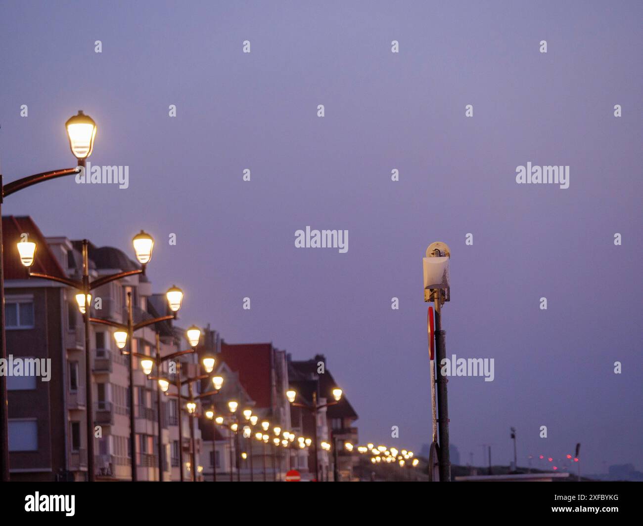 Row of street lamps along a promenade at dusk, the facades of the ...