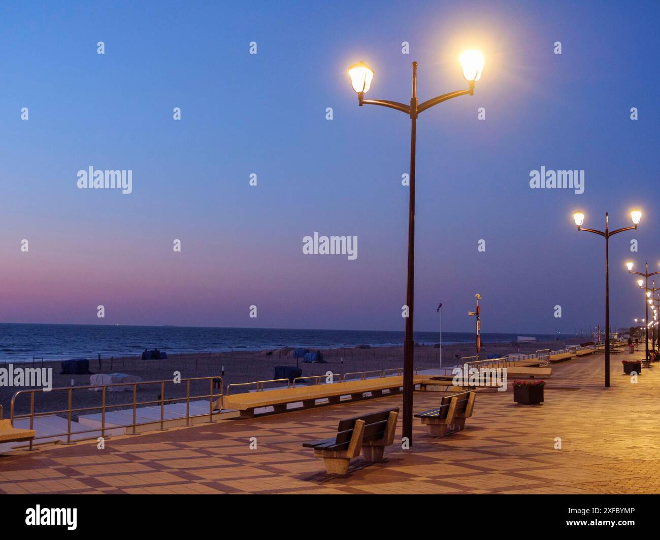 Night promenade with illuminated street lamps and benches, De Haan ...
