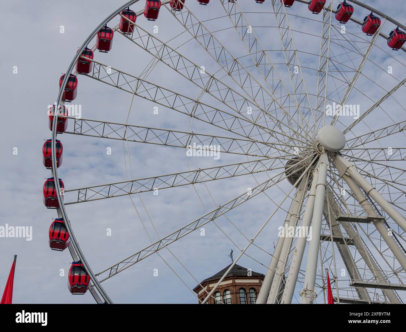 A large Ferris wheel with striking red gondolas that dominates the sky ...