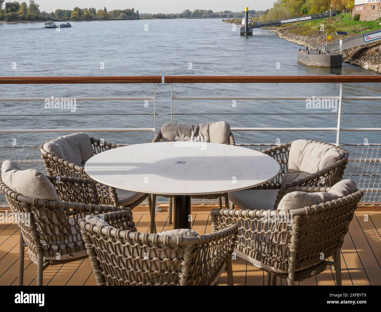 A cosy terrace with woven chairs and table overlooking a river ...