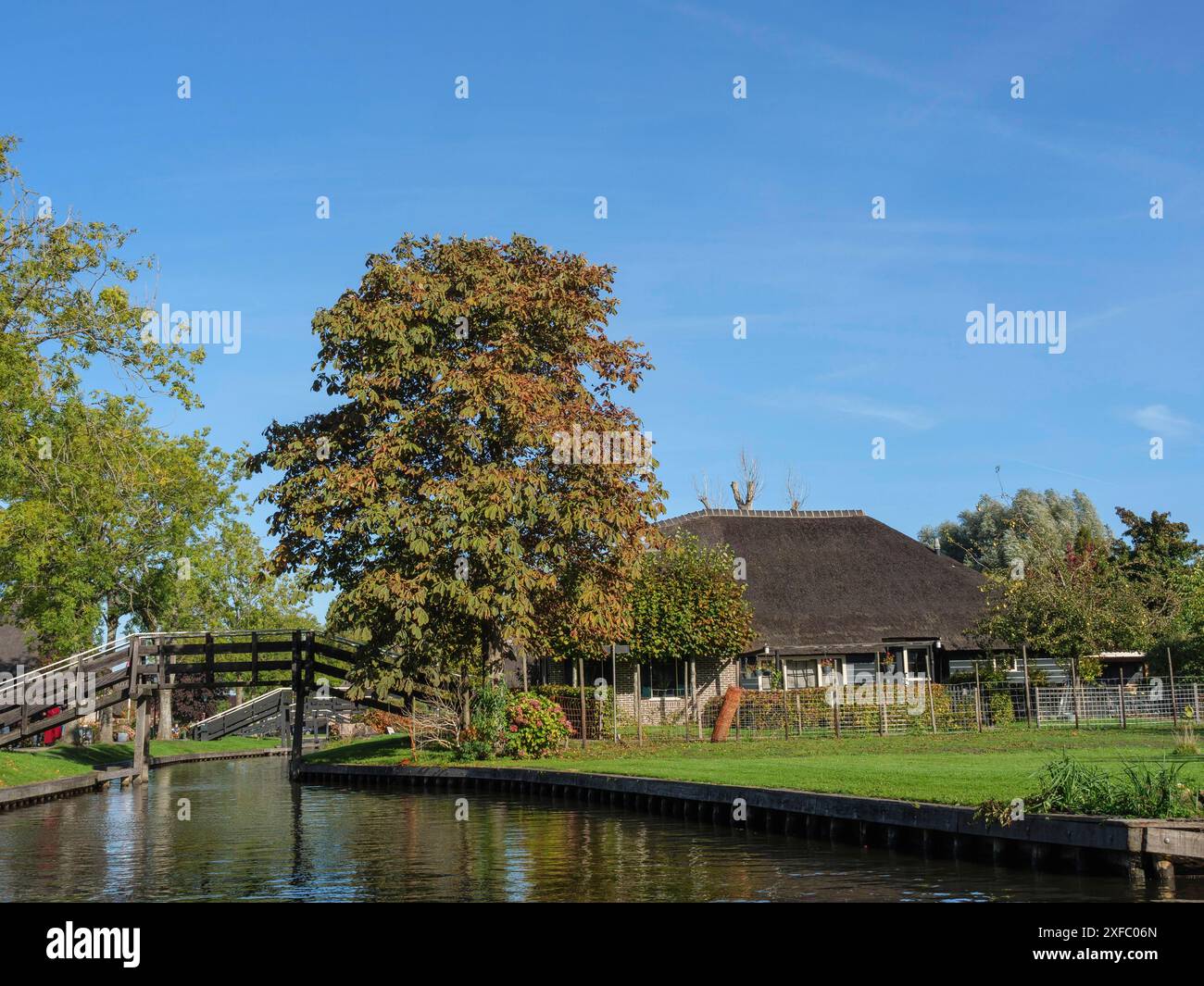 Traditional thatched house with well-kept garden, surrounded by a canal ...