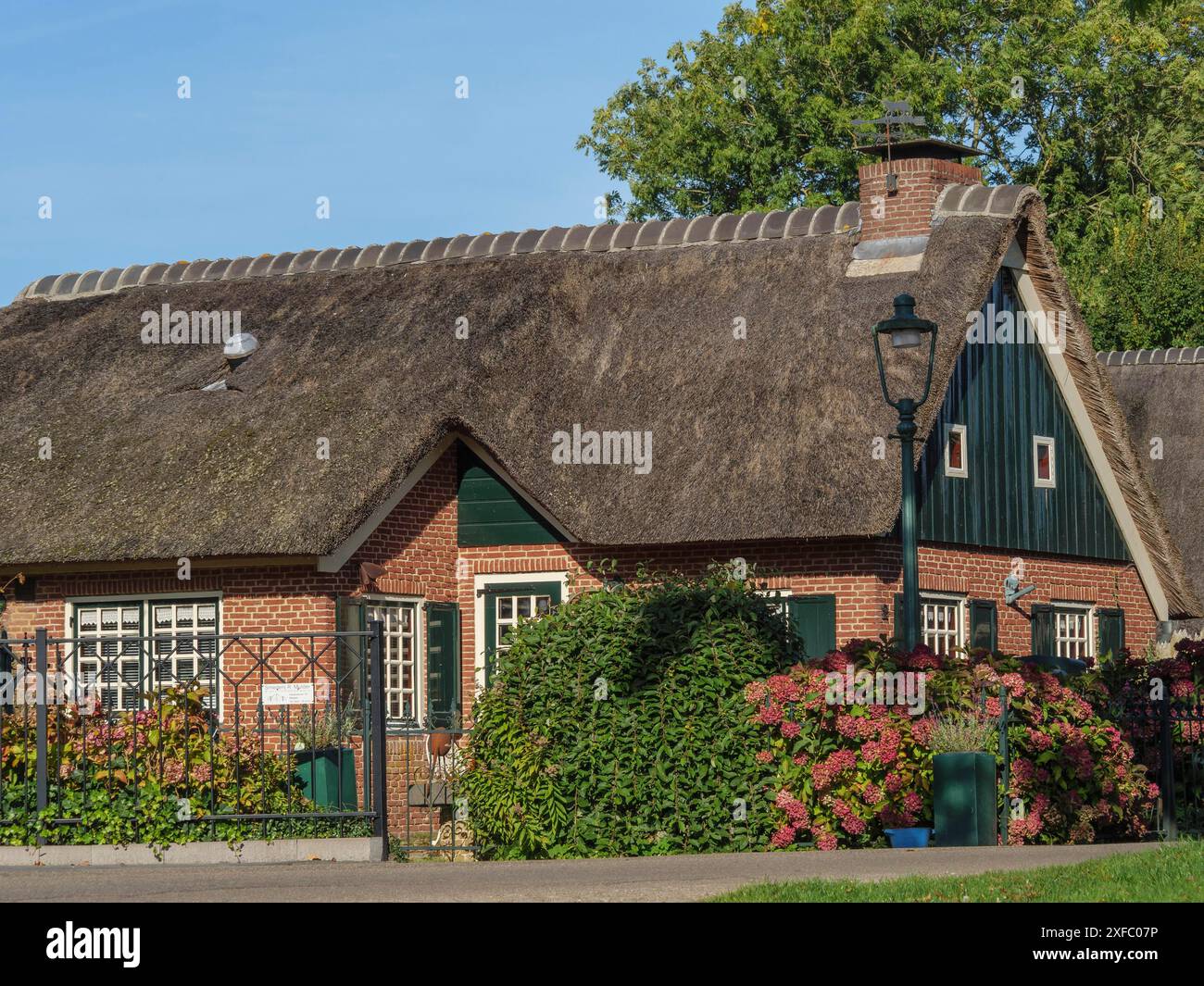Cosy brick house with thatched roof and garden, illuminated by a ...