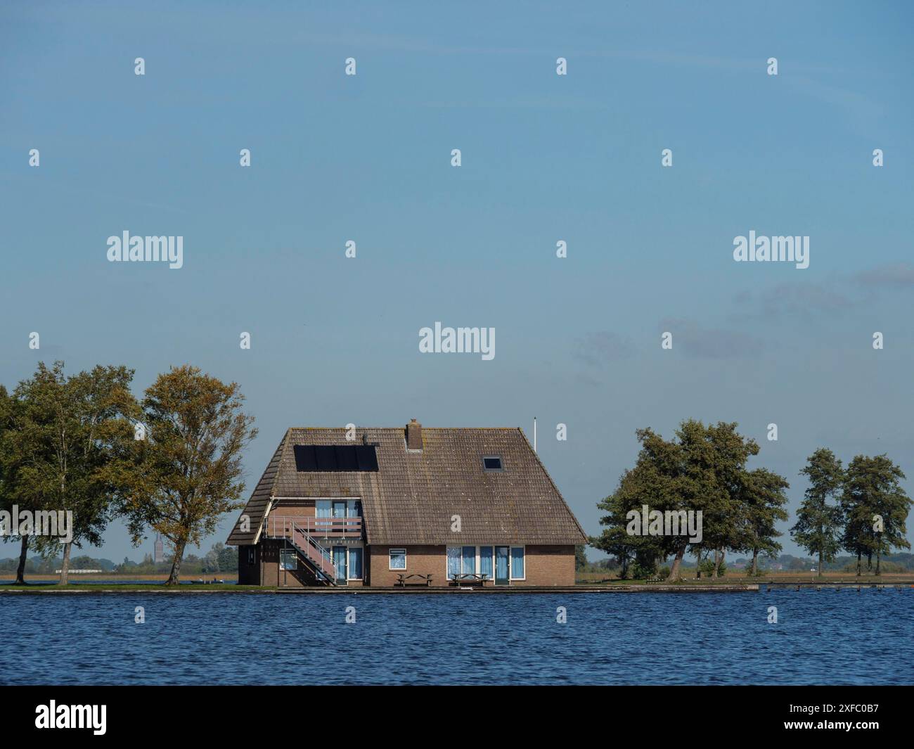 House on the lakeshore surrounded by trees and clear skies, giethoorn ...