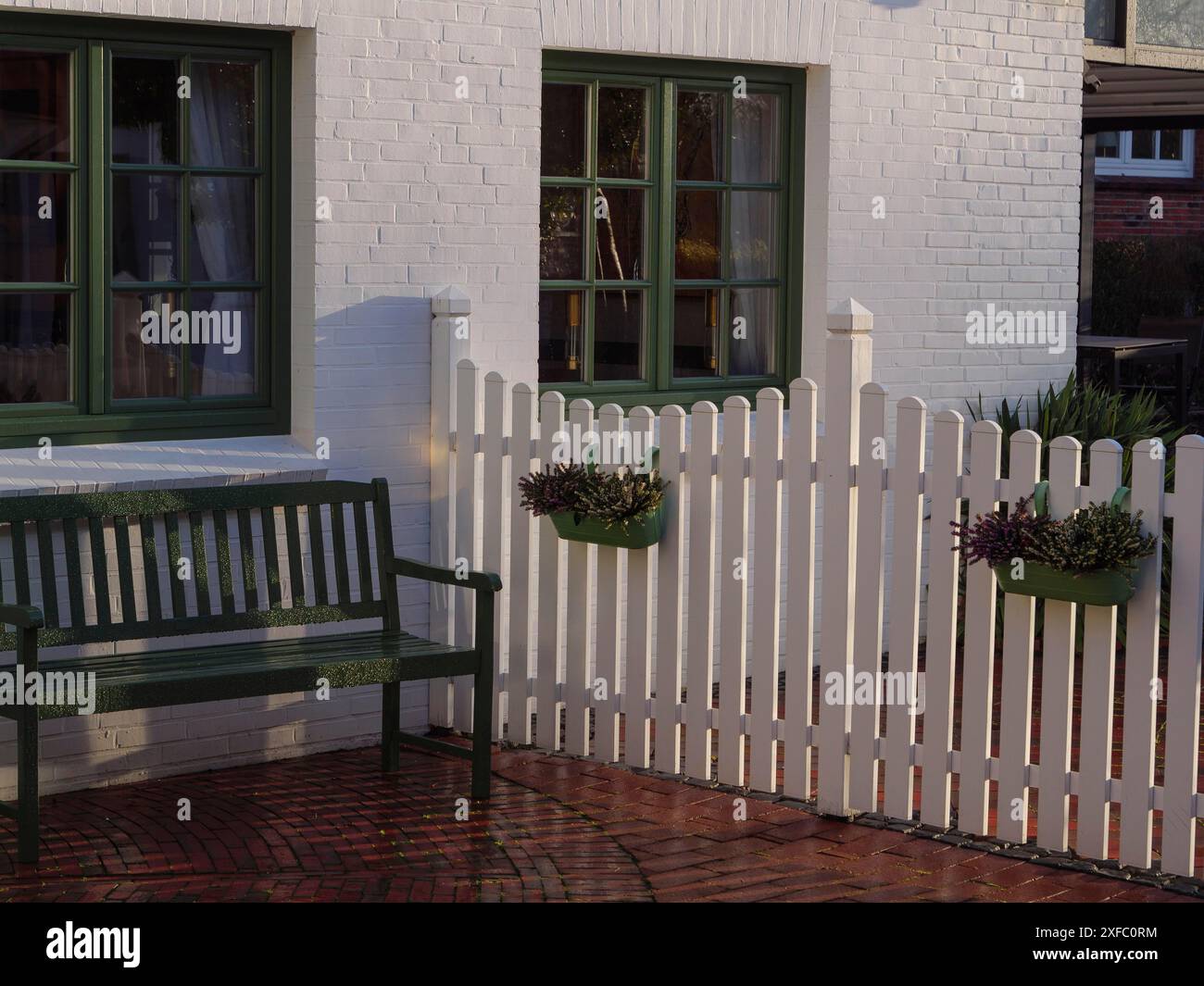 Cosy garden scene with white painted fence and bench standing next to a ...