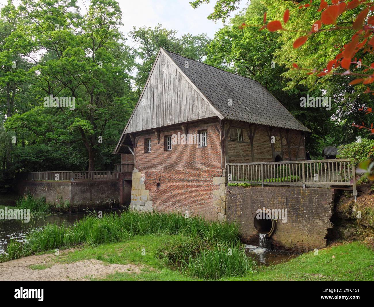 Old brick house with wooden structure next to a river, surrounded by ...