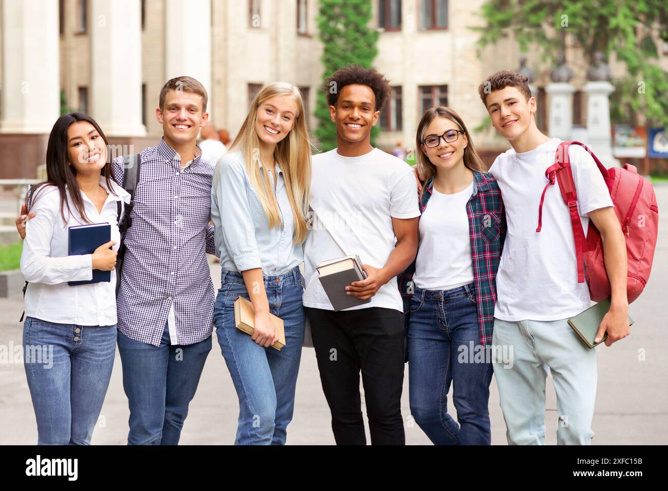 Diverse students in campus, posing in front of university Stock Photo ...