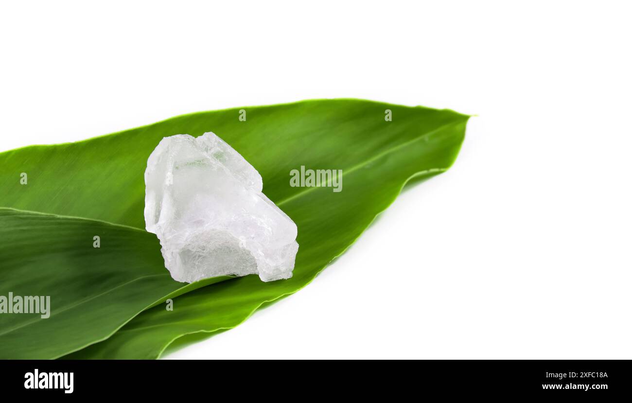 White crystal clear alum cube on green leaf isolated on white ...