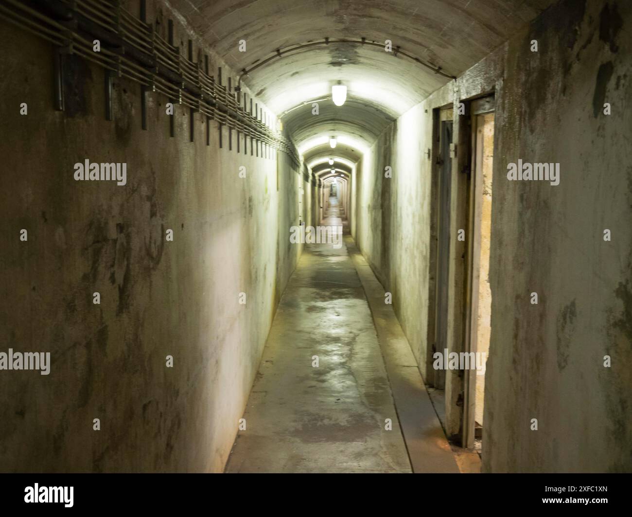 A long, closely lit tunnel with concrete walls and an oppressive ...