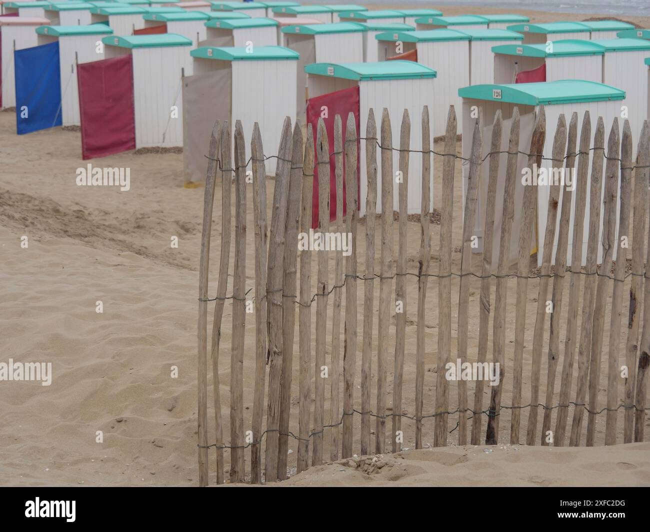 Beach scene with wooden fence and colourful beach huts in the sand ...
