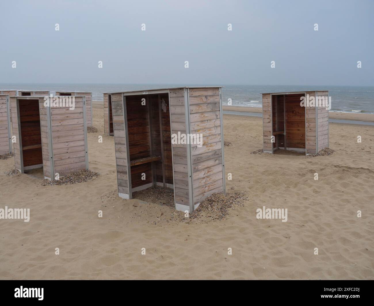 Wooden beach cabins on a deserted sandy beach with calm sea in the ...