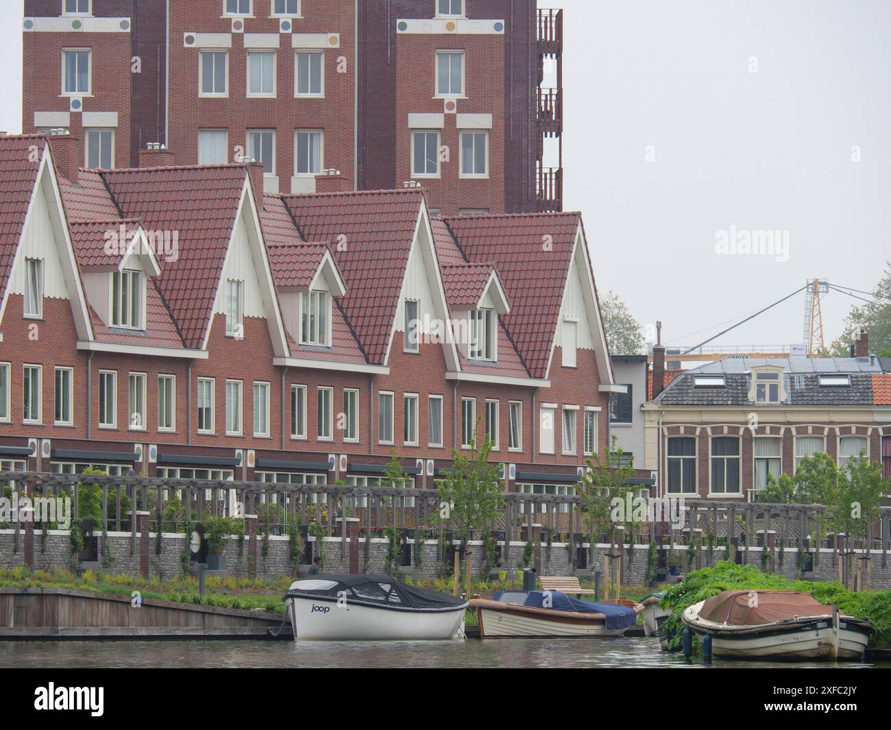 Rows of red brick houses along a river, with boats in the water and ...
