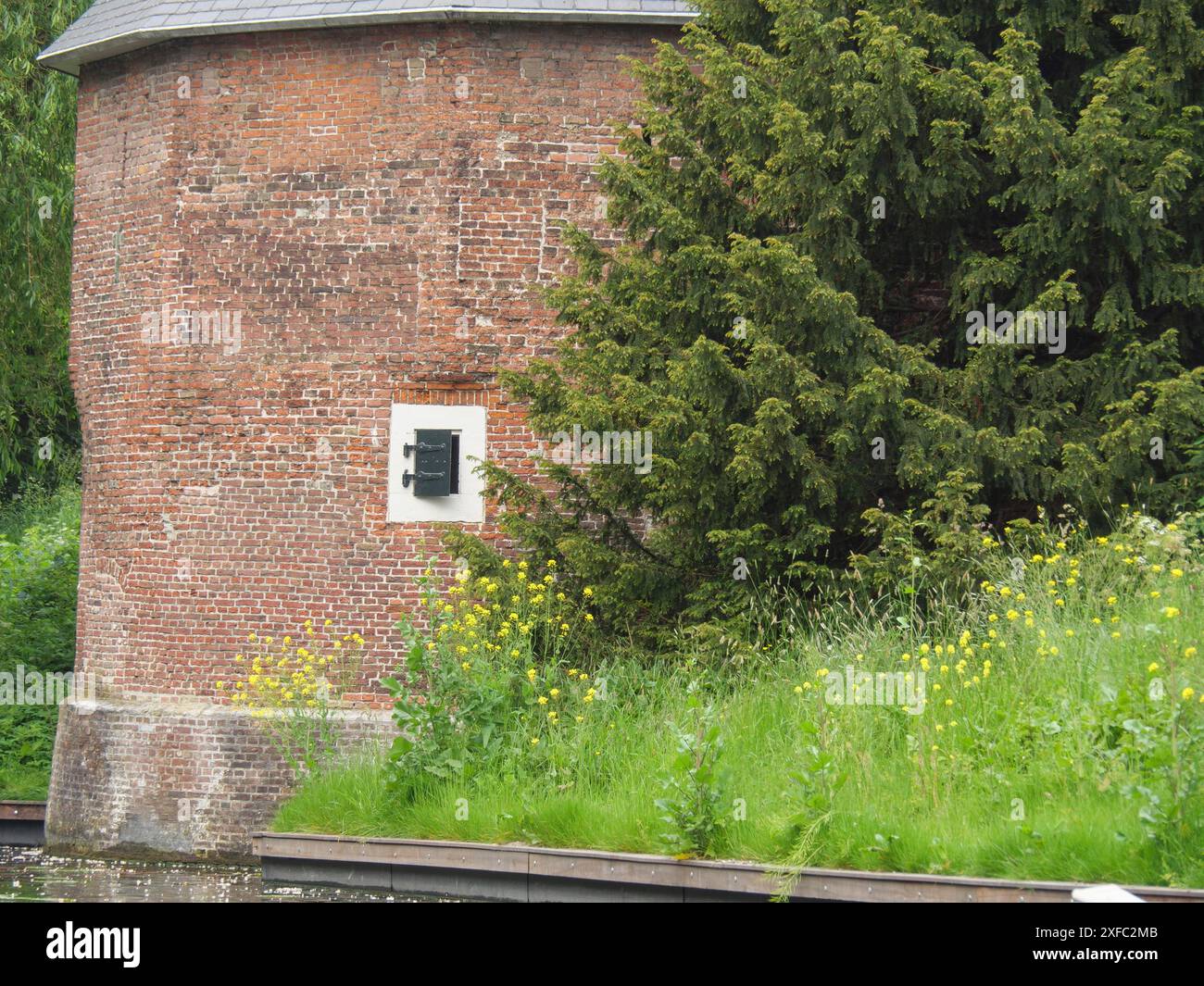 Historic brick building concealed by lush vegetation and water in the ...