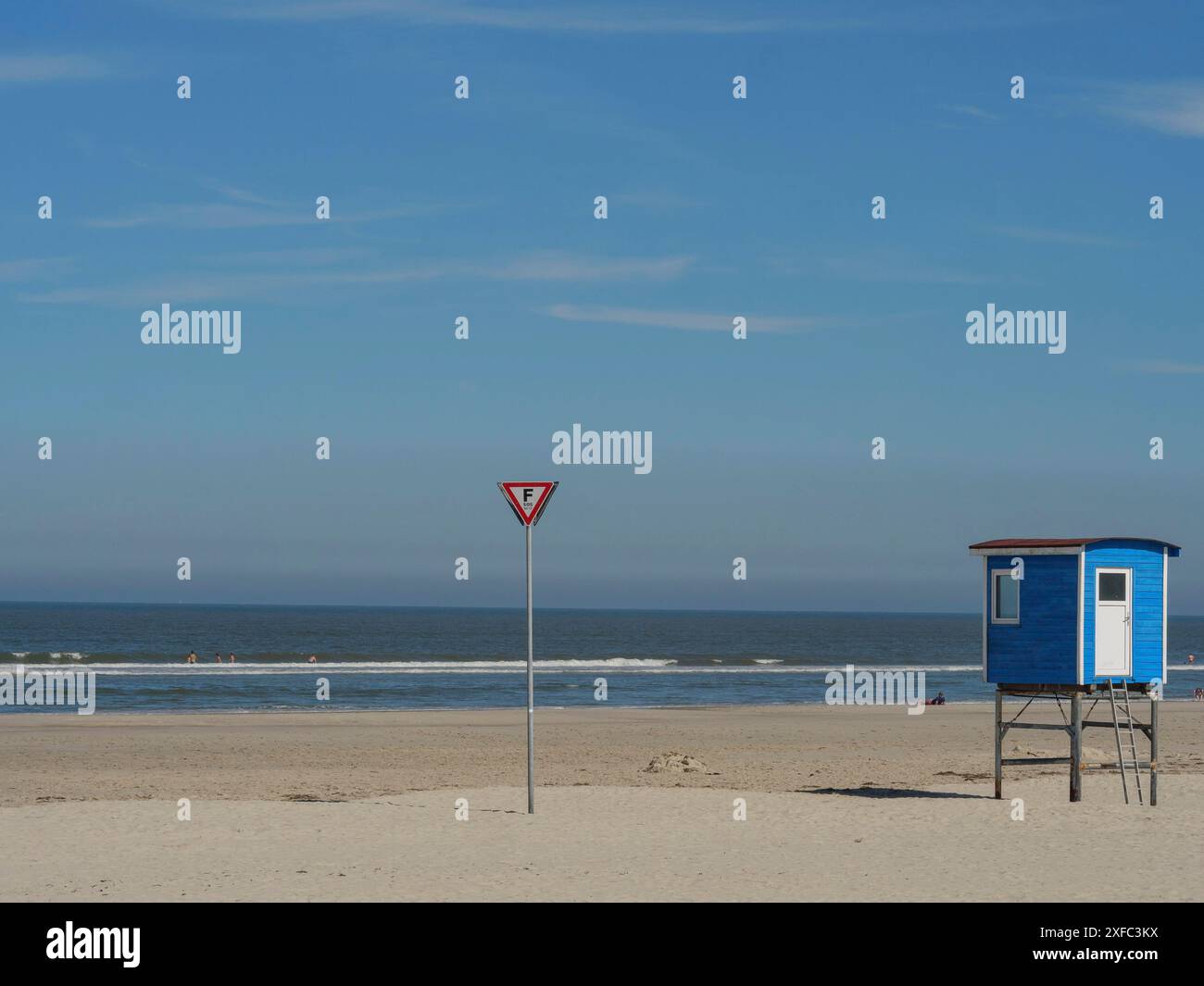 Sandy beach beach with a blue wooden hut and a traffic sign in front of ...