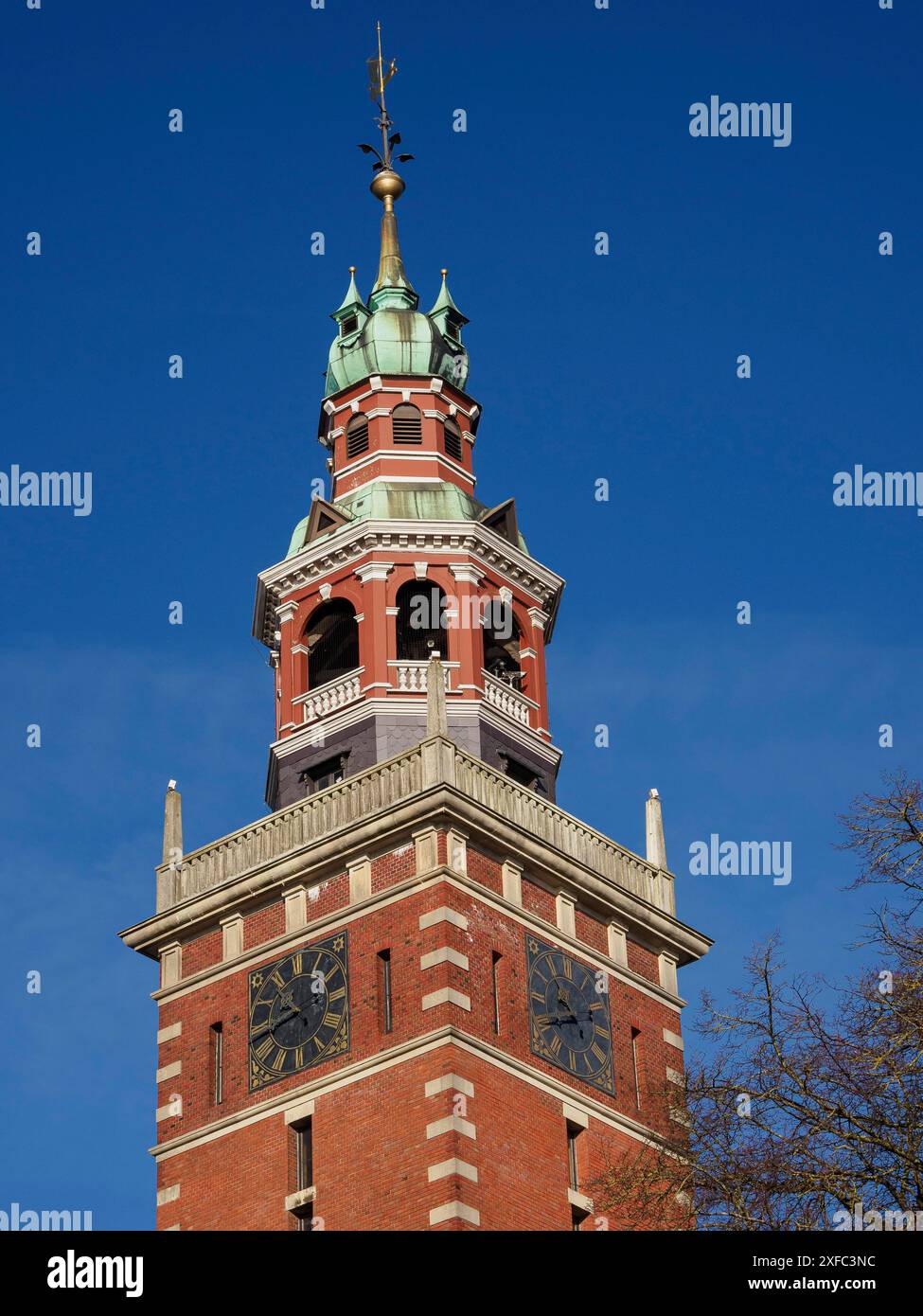Historic brick tower with clock and green copper roof under a blue sky ...