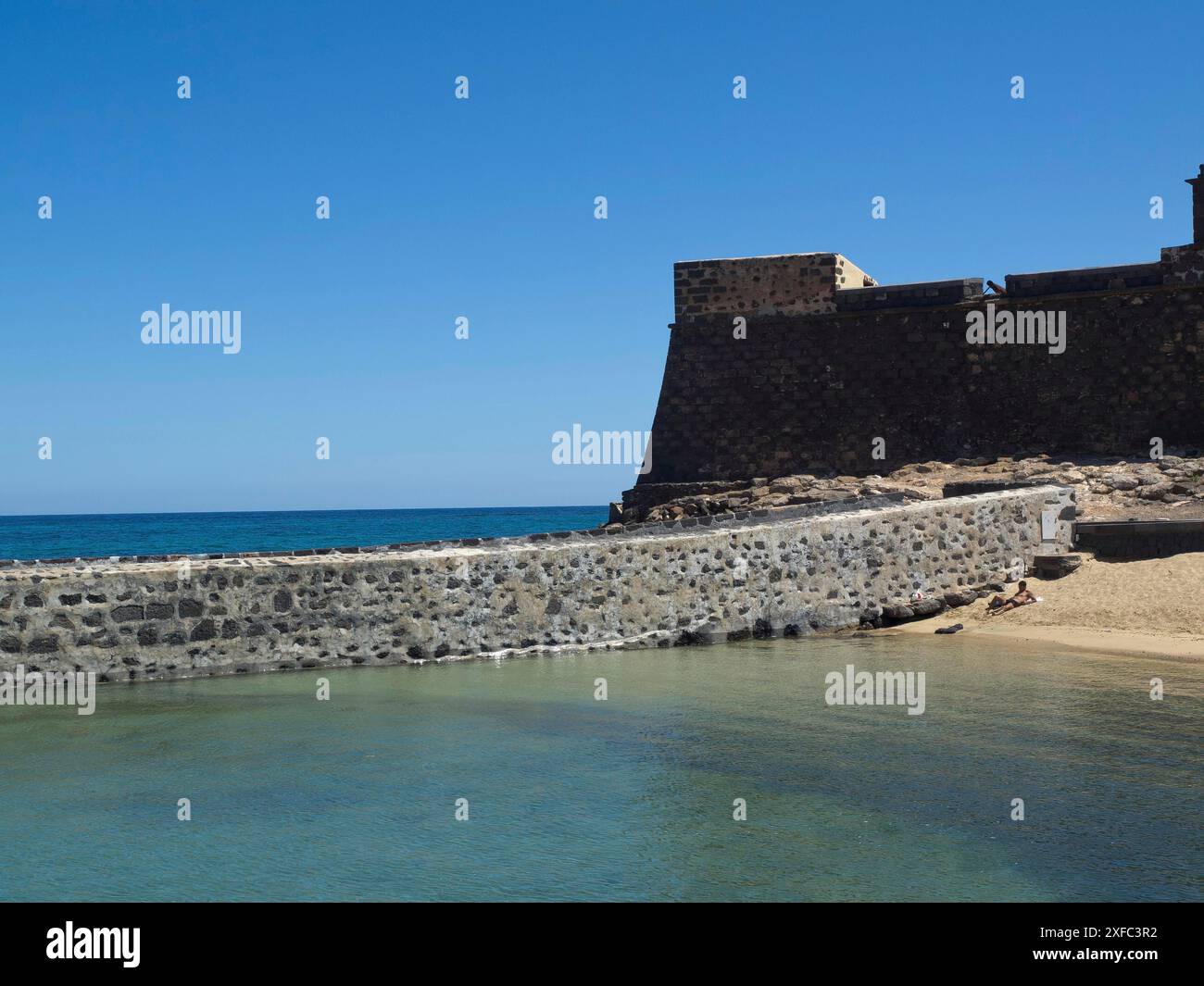 An old coastal fort with a large stone wall stretches to the edge of ...