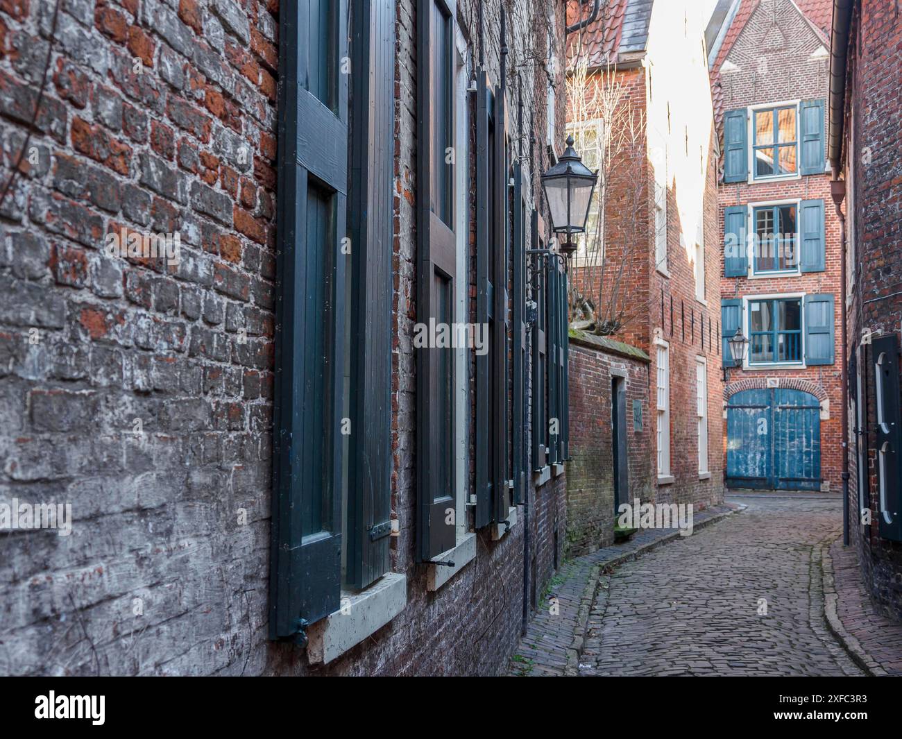 Narrow, cobbled alley with historic buildings and window shades, empty ...