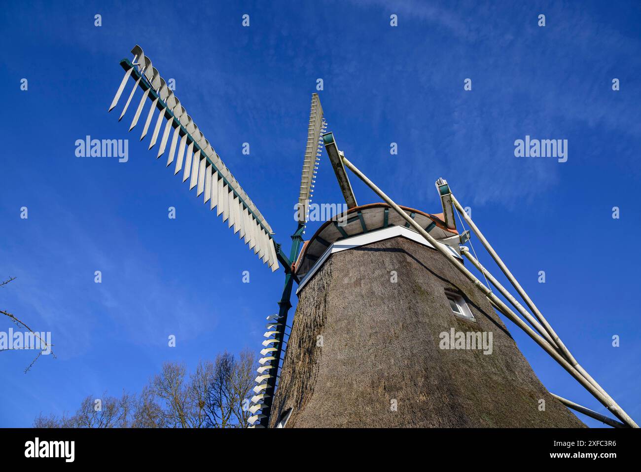 Traditional windmill with large wooden sails in front of a bright blue ...