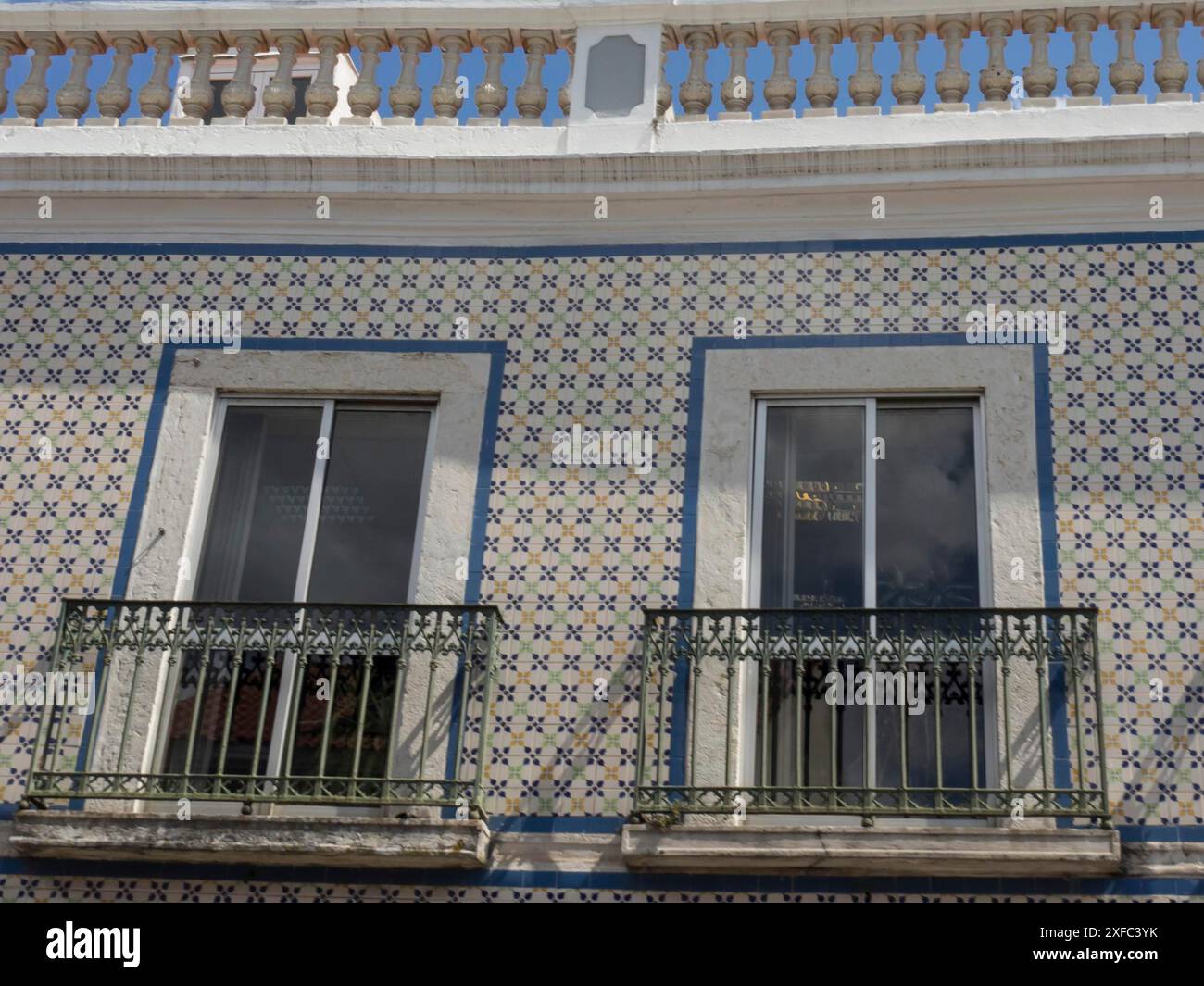 Two balconies with wrought iron railings in front of a wall with ...