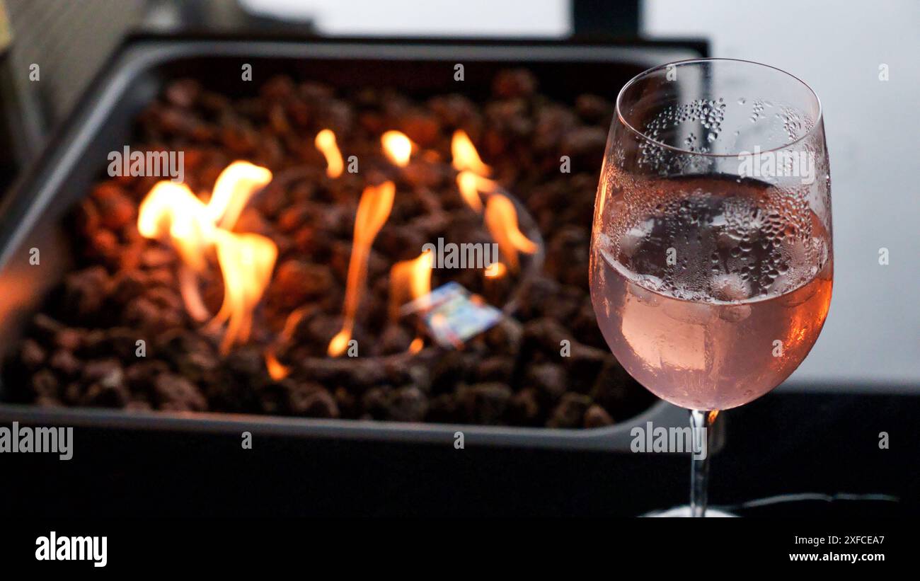 Stone firepit with fire flames and glass of wine. Summer camping ...