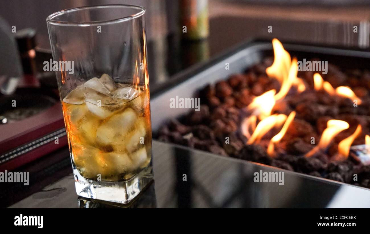 Stone firepit with fire flames and glass of whiskey. Summer camping ...