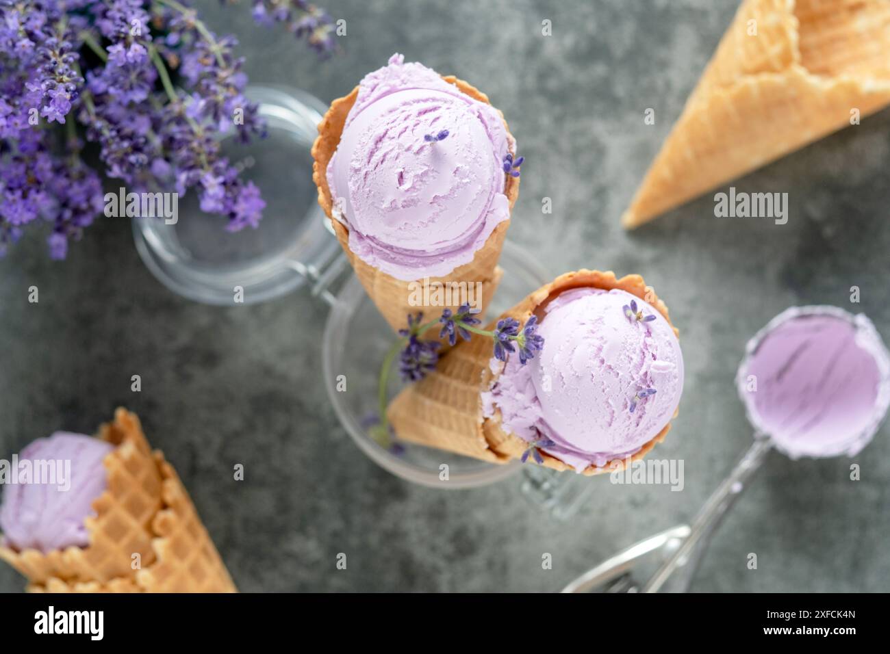 Creamy lavender ice cream in a waffle cone on a concrete background ...