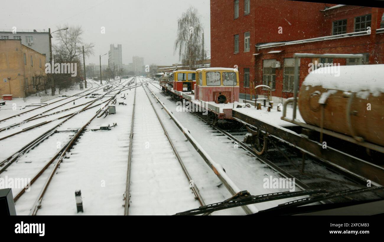 Railway tracks run through an industrial zone with an old factory. Snow ...