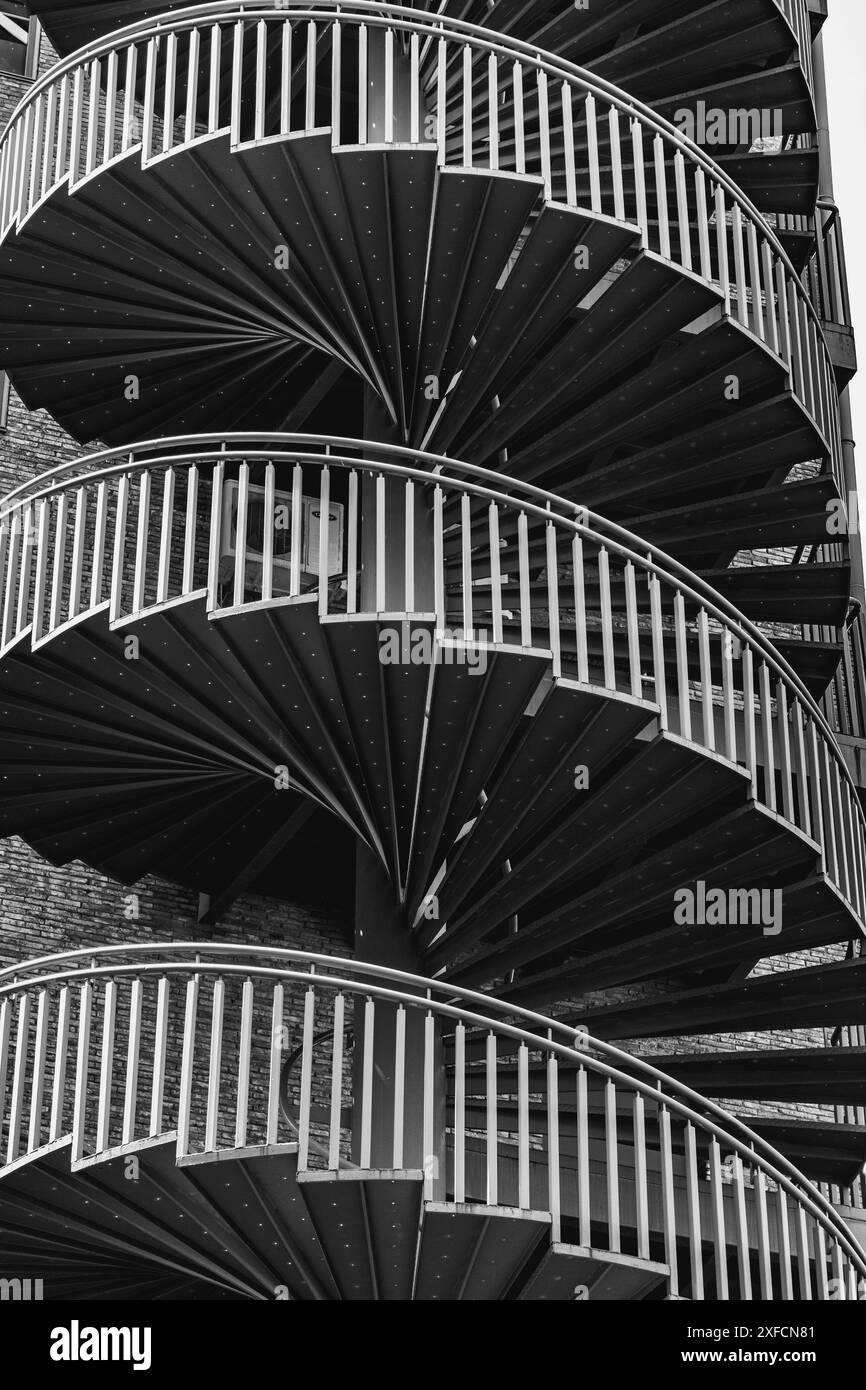 Spiral, wide and modern fire escape stairway of a brick covered ...