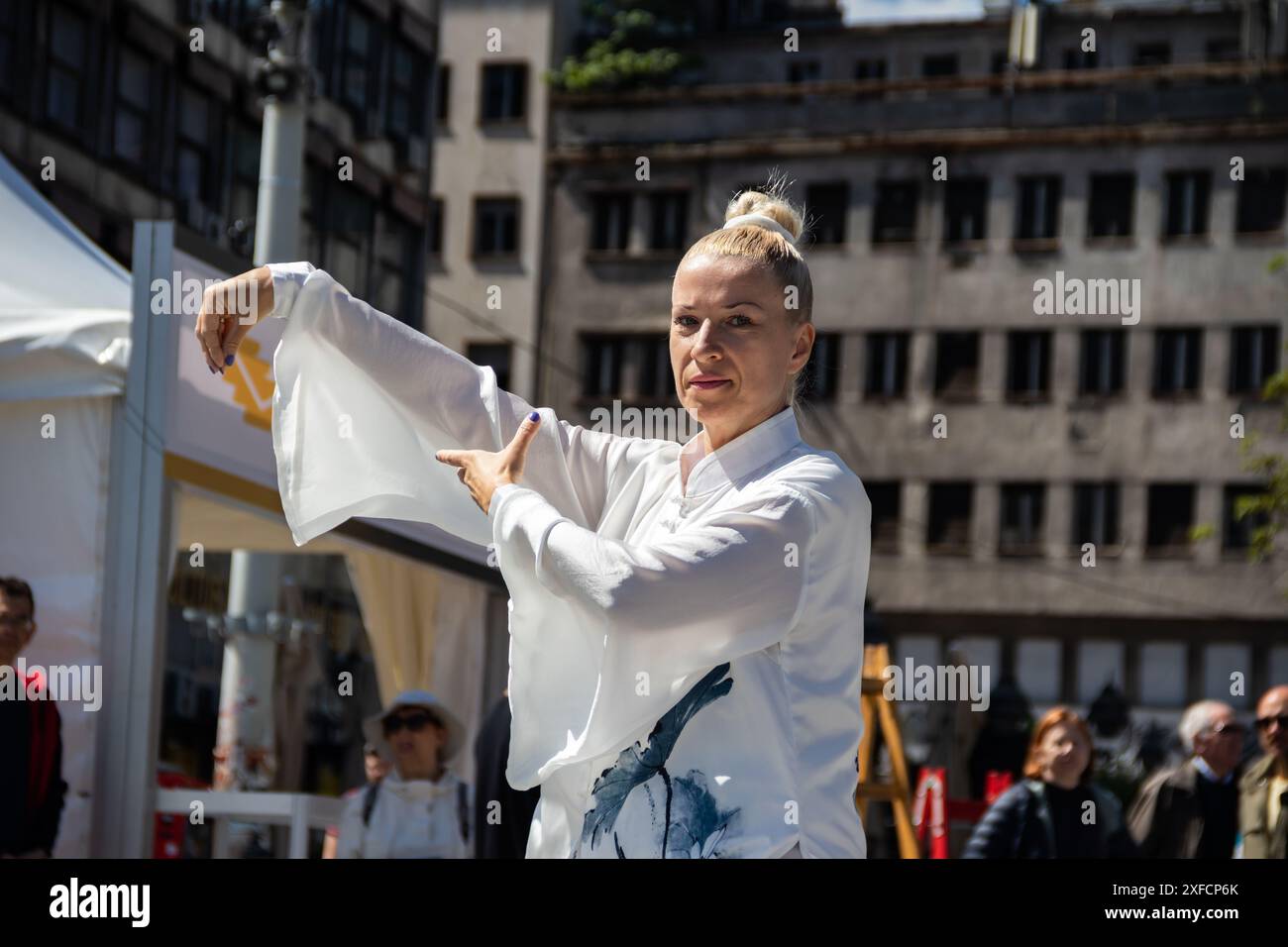 A serene Tai Chi master in a flowing white suit gracefully performs on ...