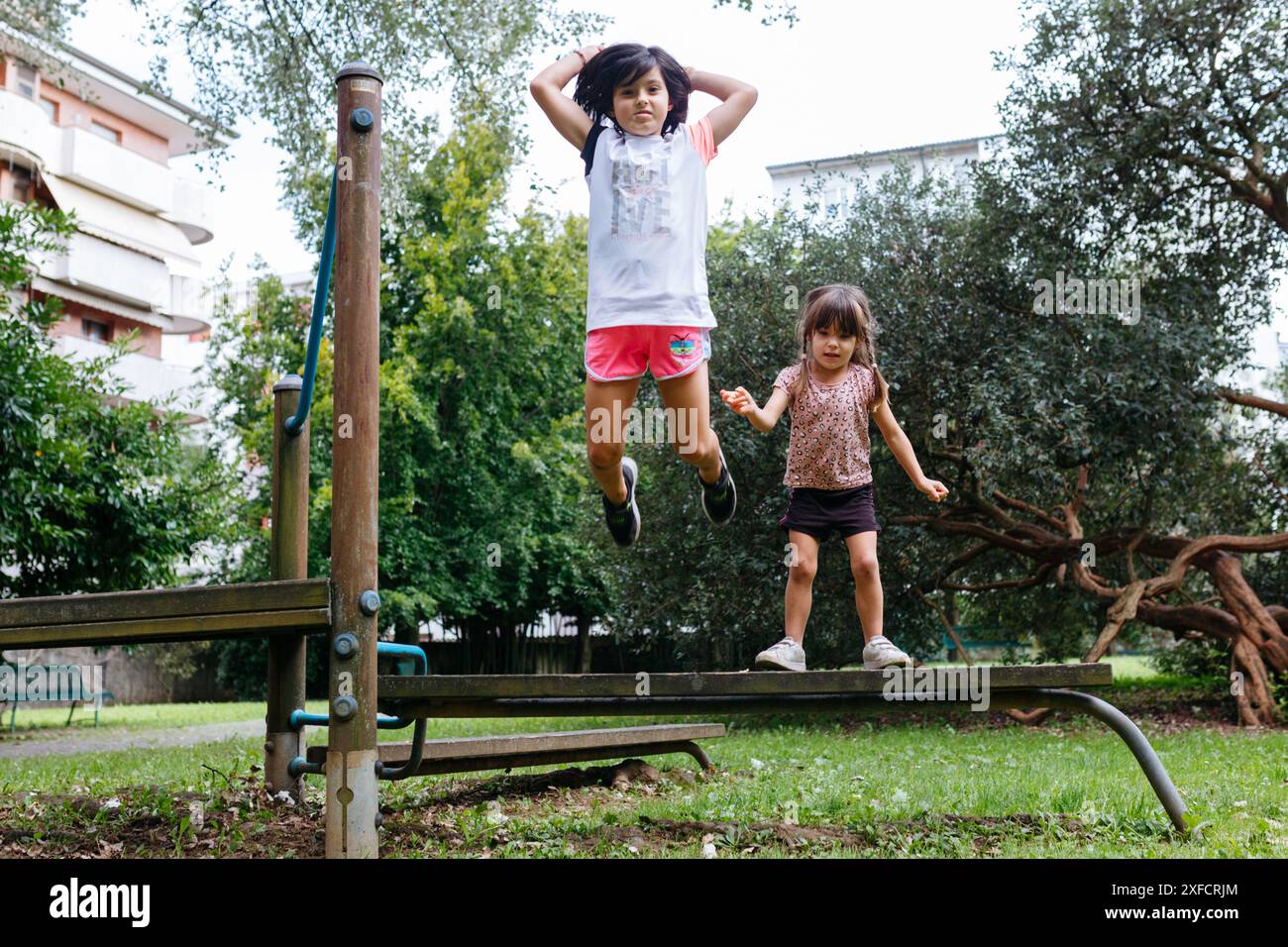 two children jumping from the wooden bench in the park Stock Photo - Alamy