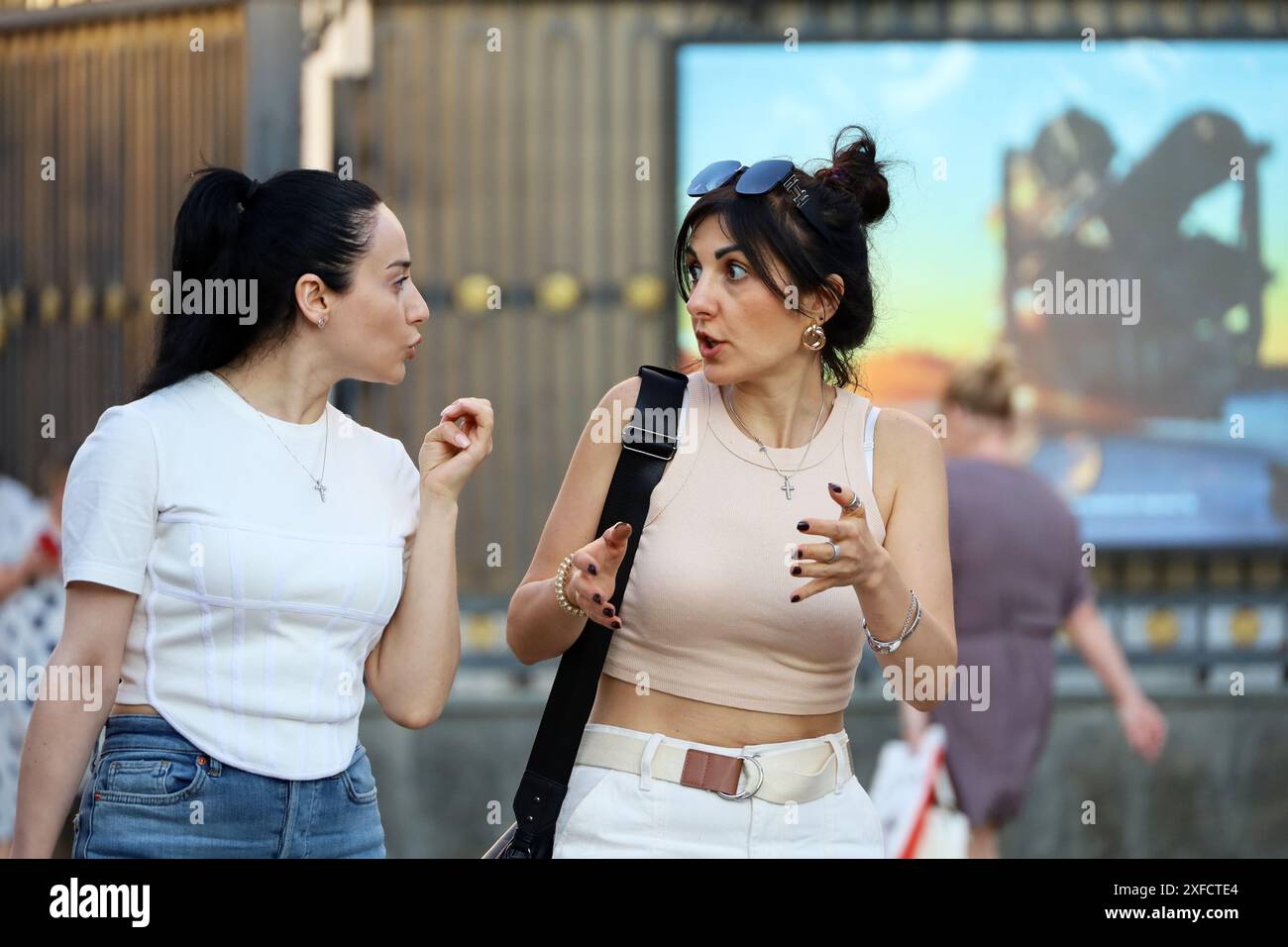 Two young women talking emotional on city street in summer Stock Photo ...