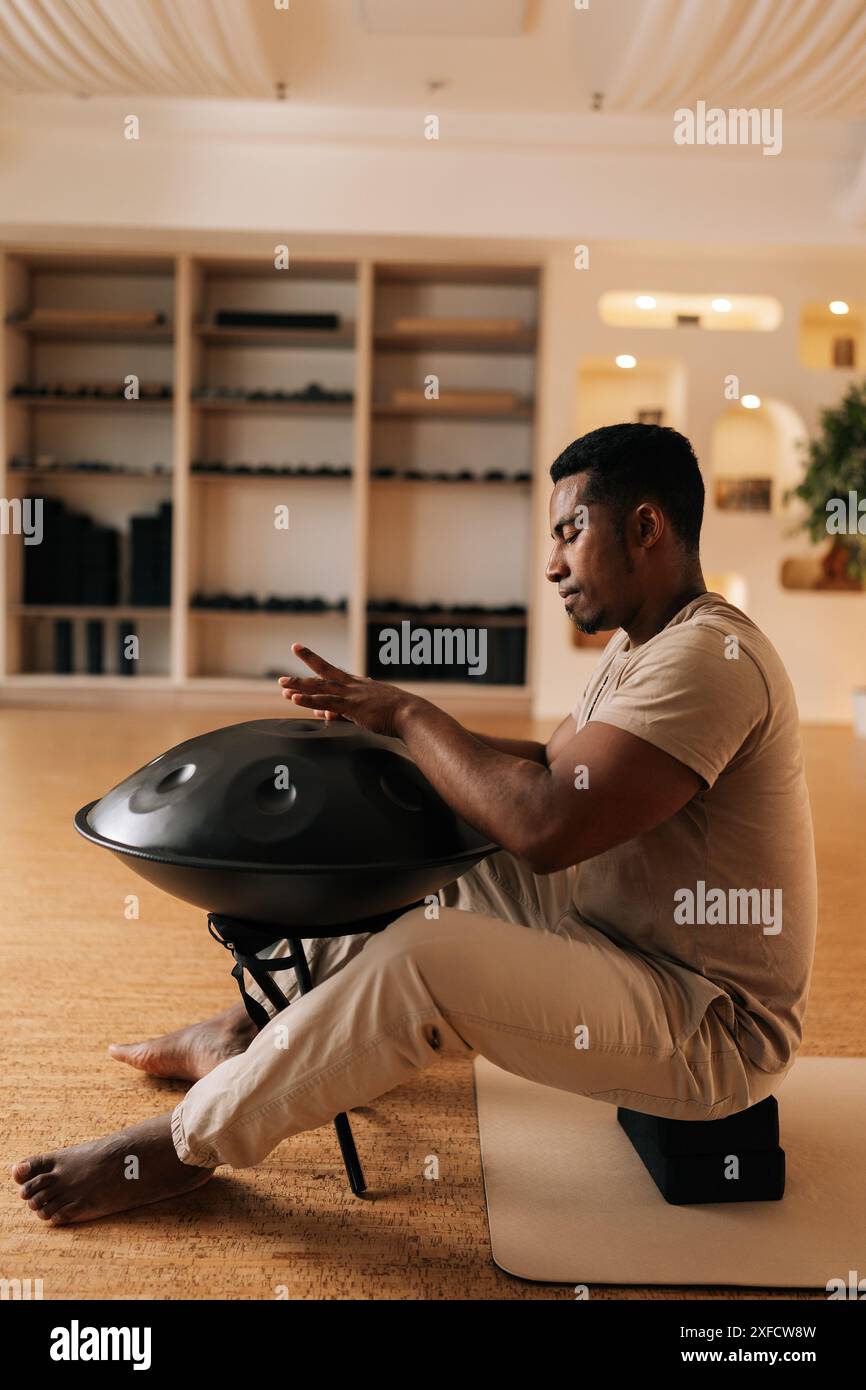Vertical side view of African drummer in trance drumming rhythm on ...