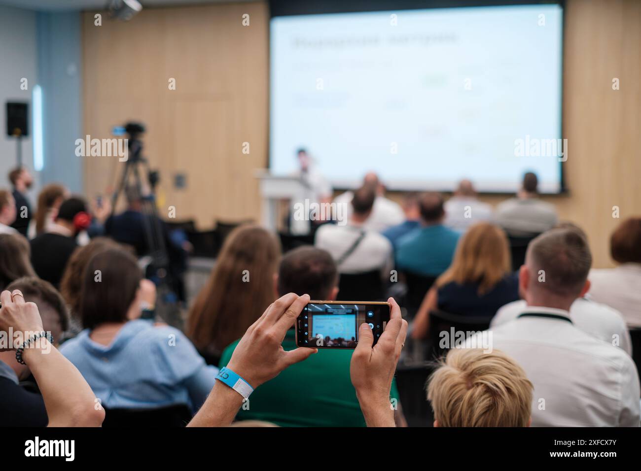 Audience members taking photos and notes while attending a tech ...