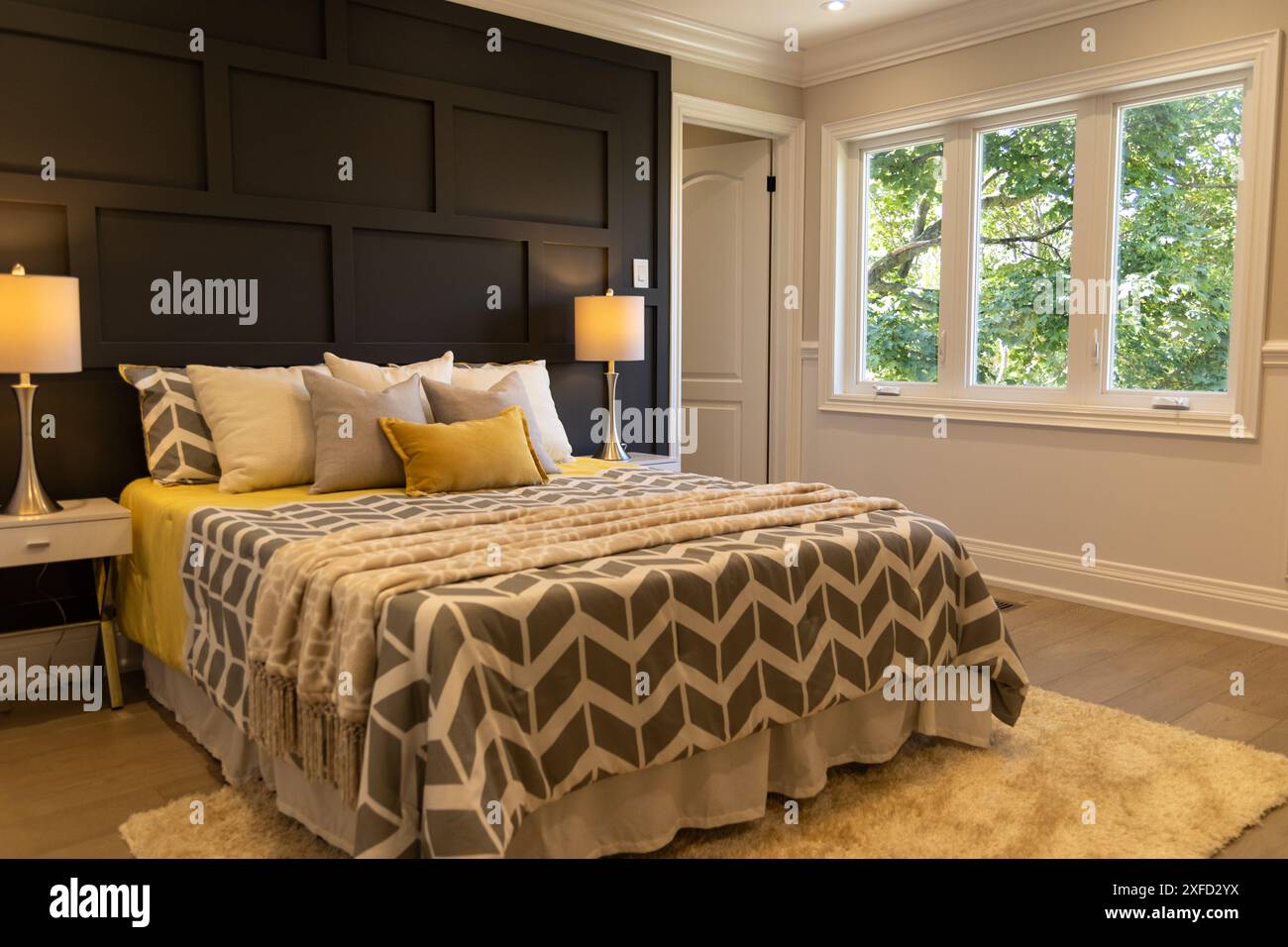 Brightly-lit bedroom - large bed with geometric-patterned comforter and ...