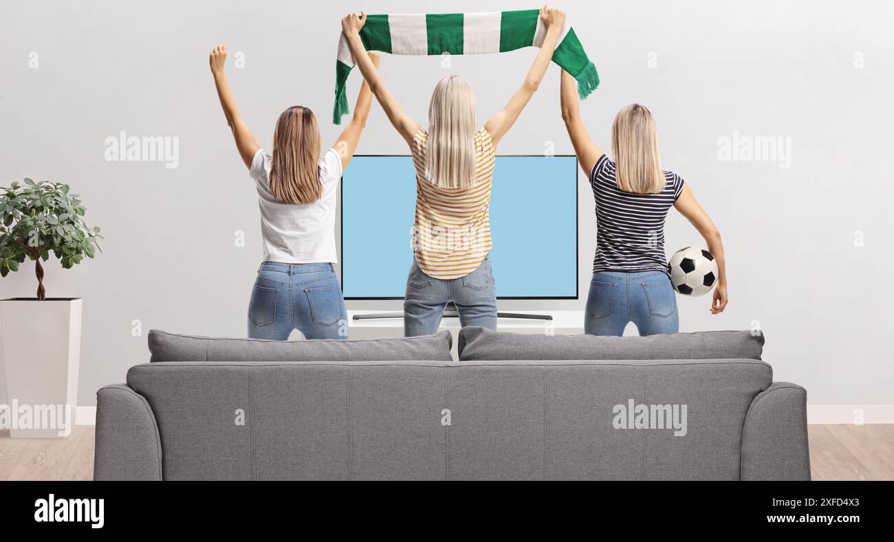 Rear view shot of excited young women cheering and watching football on ...