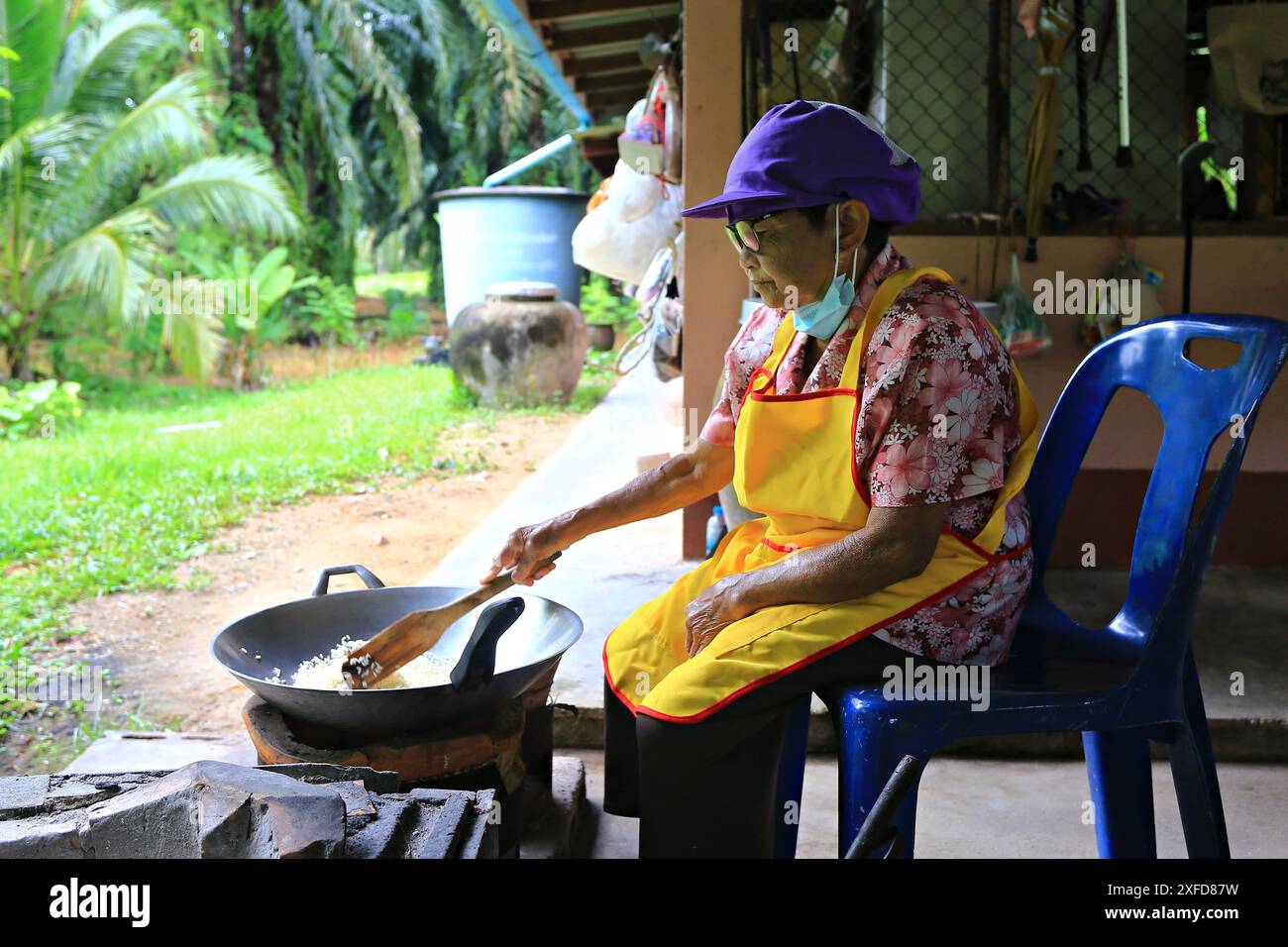 An old woman is roasting sticky rice. For use in making Thai desserts ...