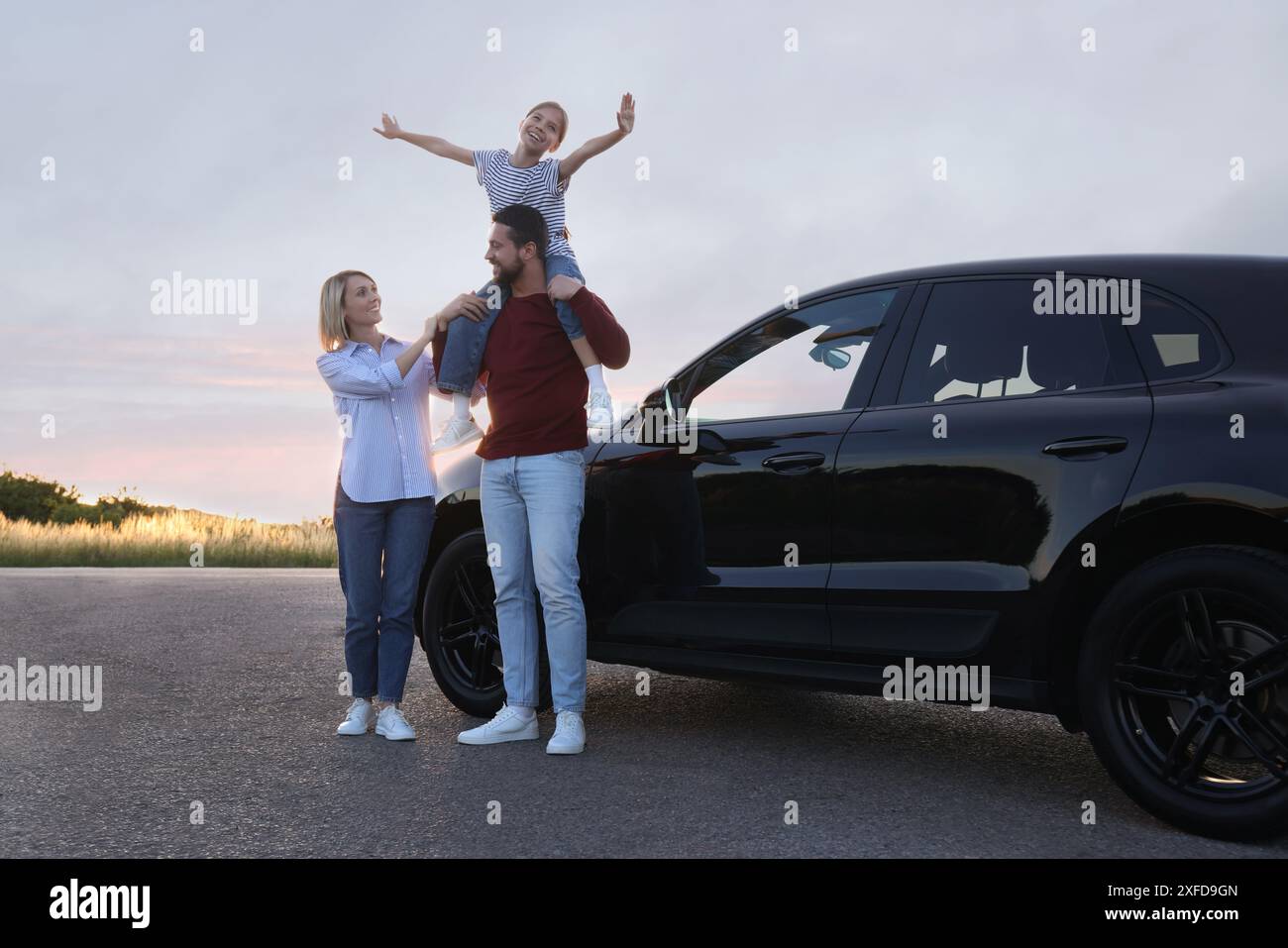 Happy parents and their daughter near car outdoors Stock Photo - Alamy