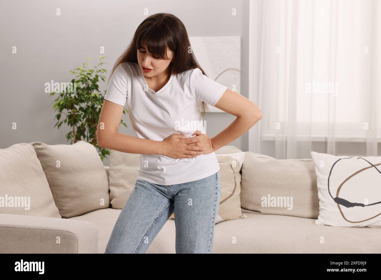 Upset woman suffering from abdominal pain at home Stock Photo - Alamy