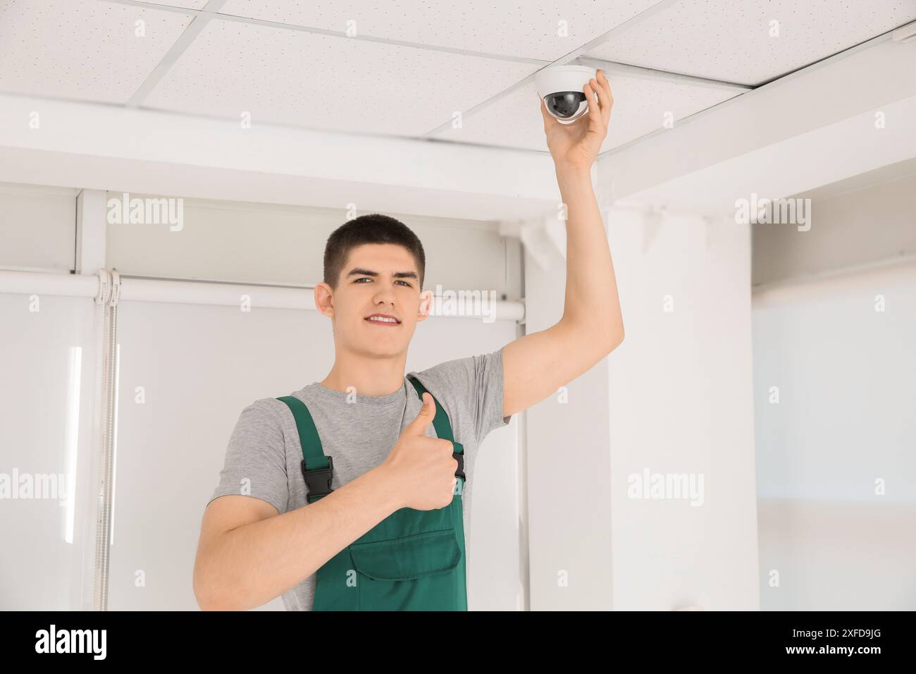 Technician showing thumbs up while installing CCTV camera on ceiling ...