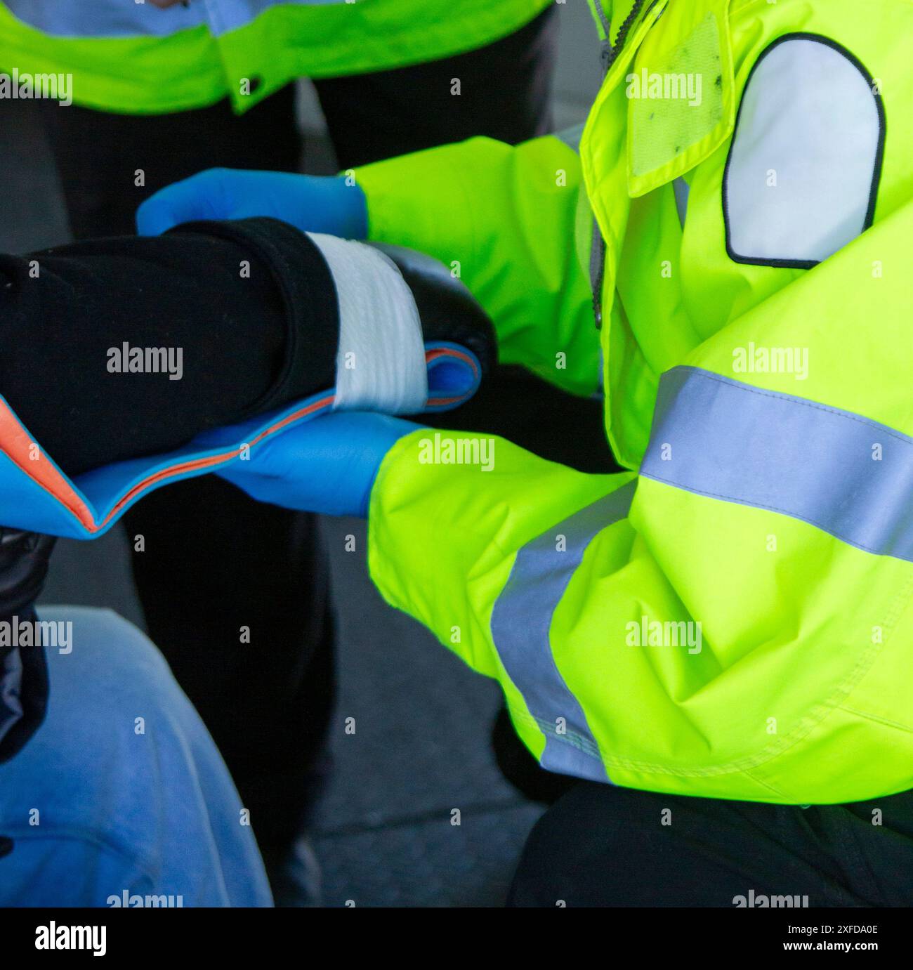 A paramedic wraps a patients arm for a demonstration of first aid ...