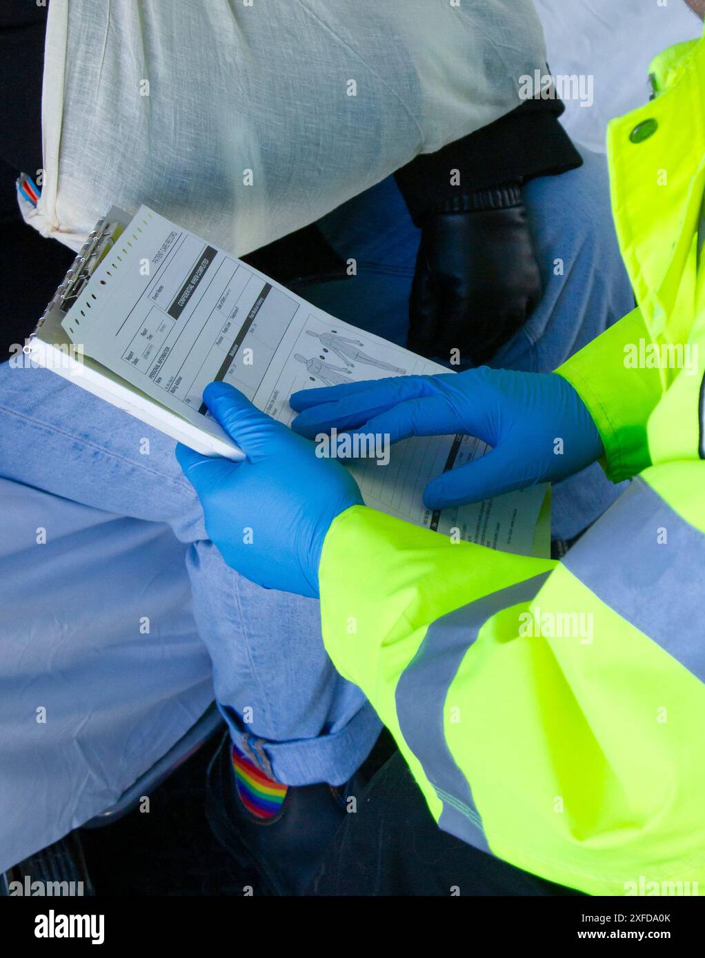 A paramedic wearing latex gloves holds a patient income form during a ...