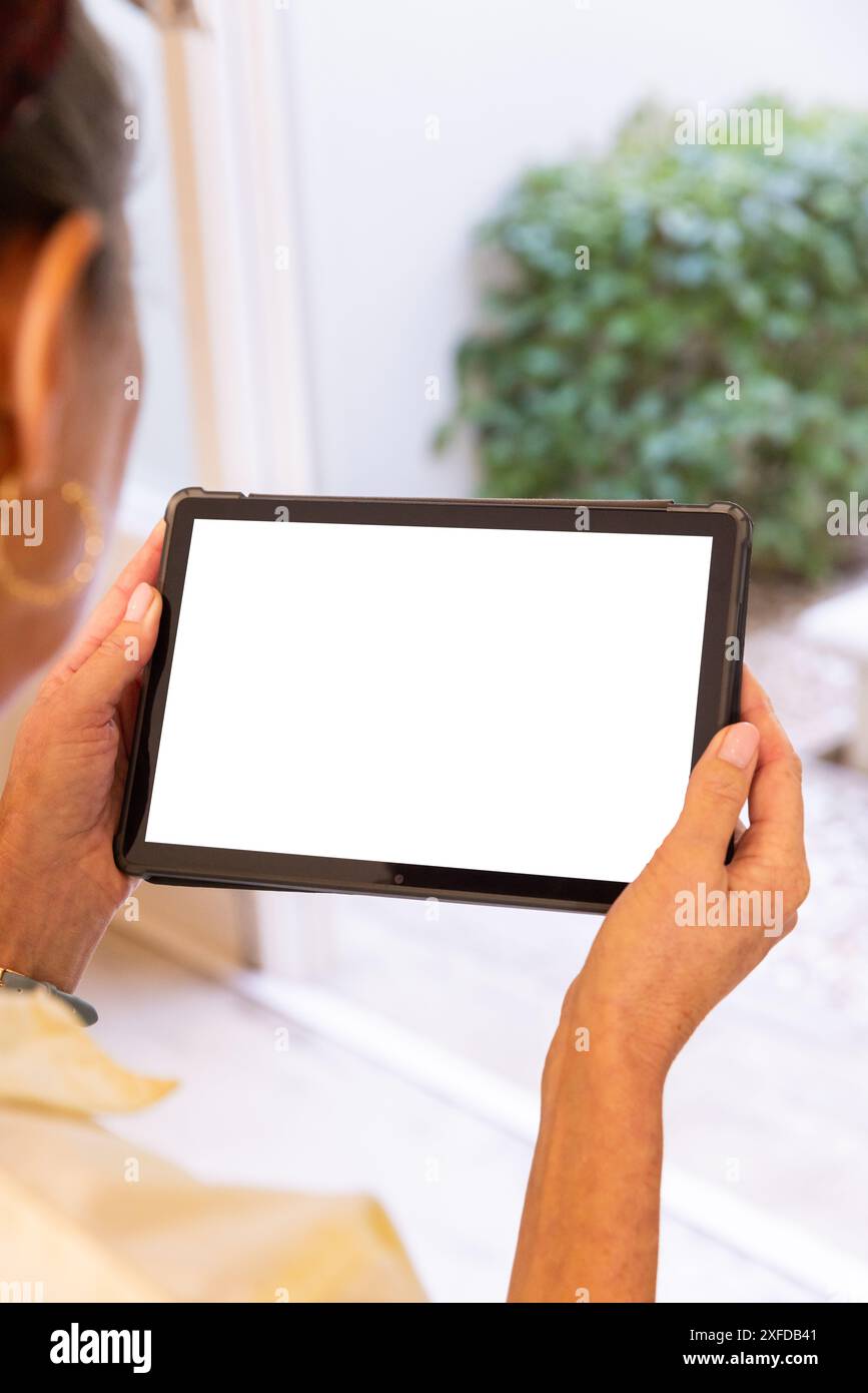 Holding tablet, woman viewing blank screen near window at home, copy ...