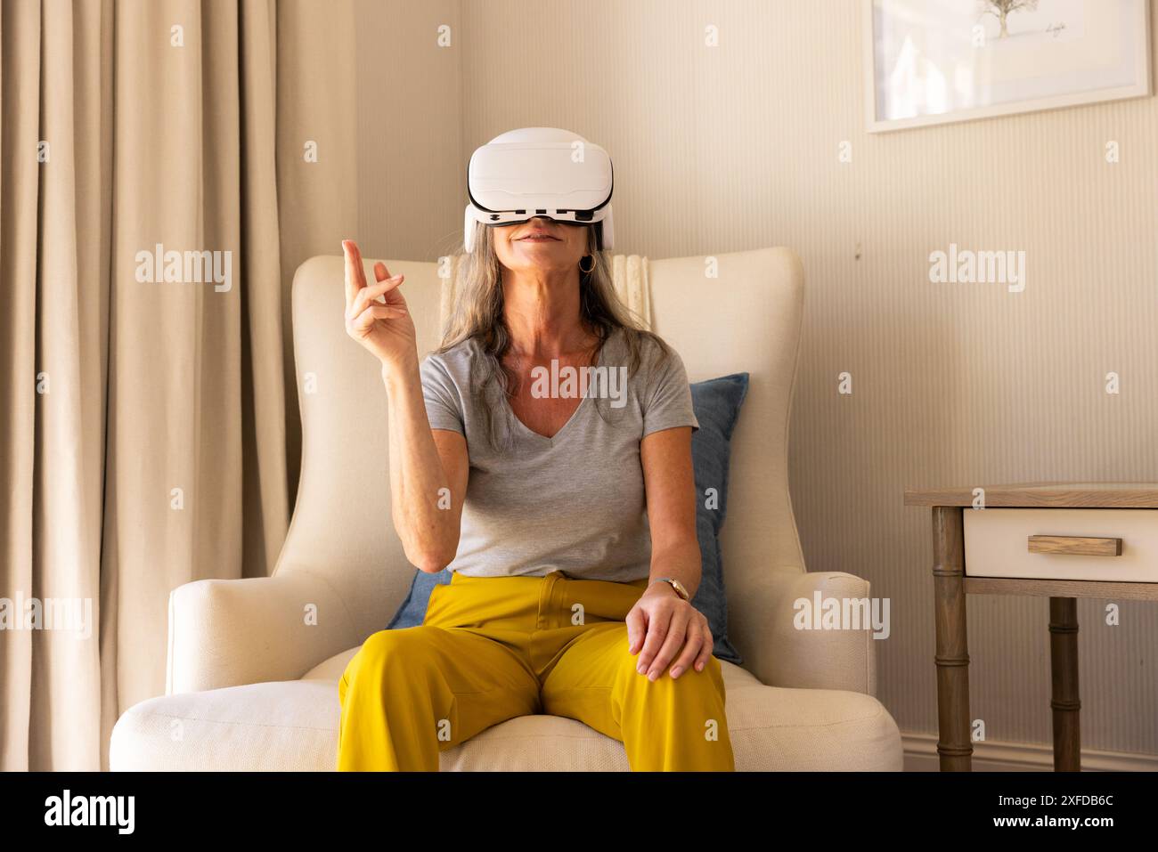 Using VR headset, mature woman sitting on chair interacting with ...