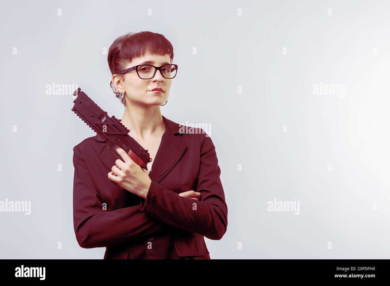 Businesswoman is holding a gun and standing with her arms crossed ...