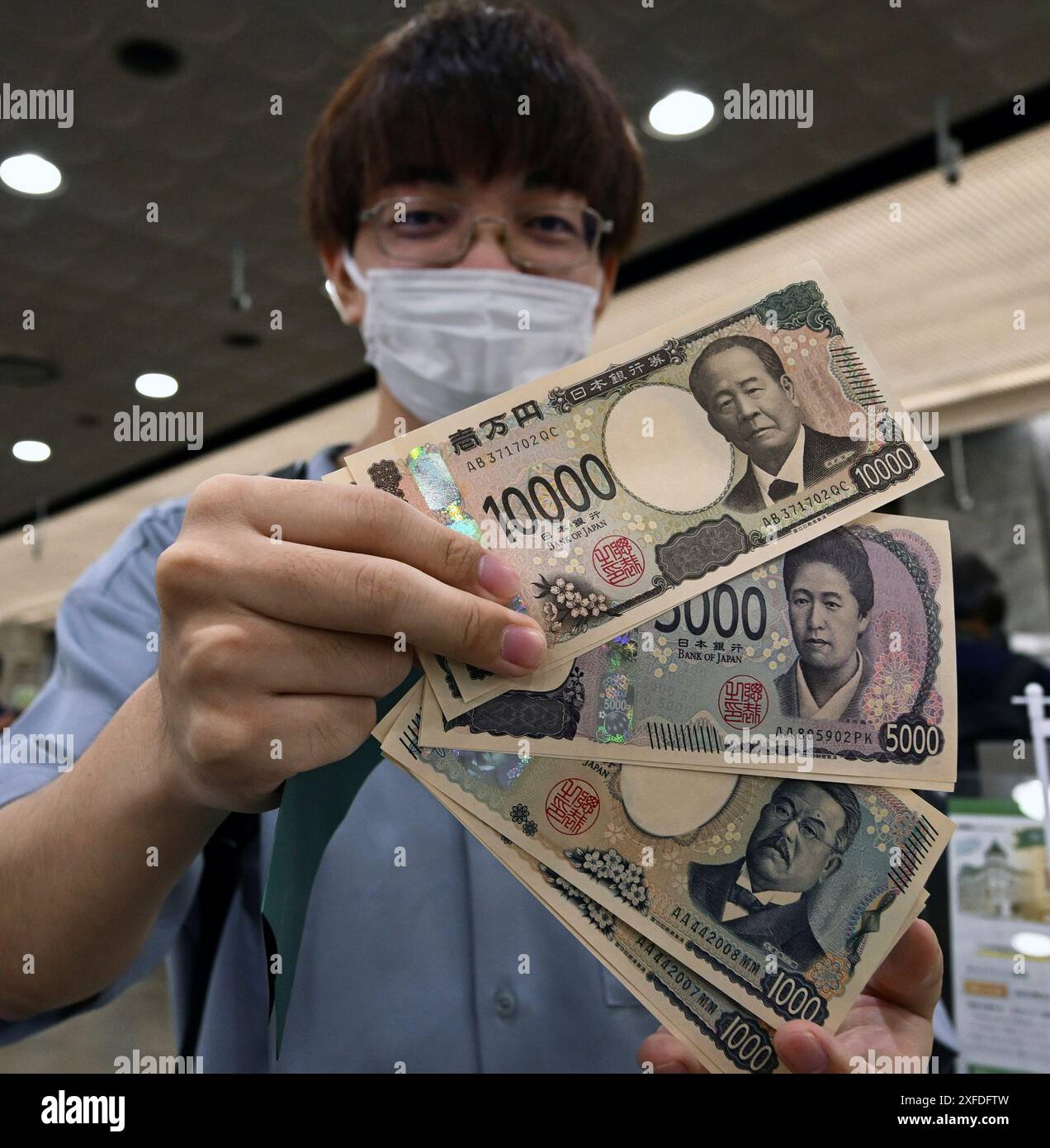 A man shows three types of new banknotes which were issued for the ...